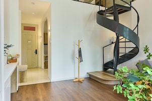 Um interior moderno com uma escada em espiral, piso de madeira e um pequeno espaço de estar.