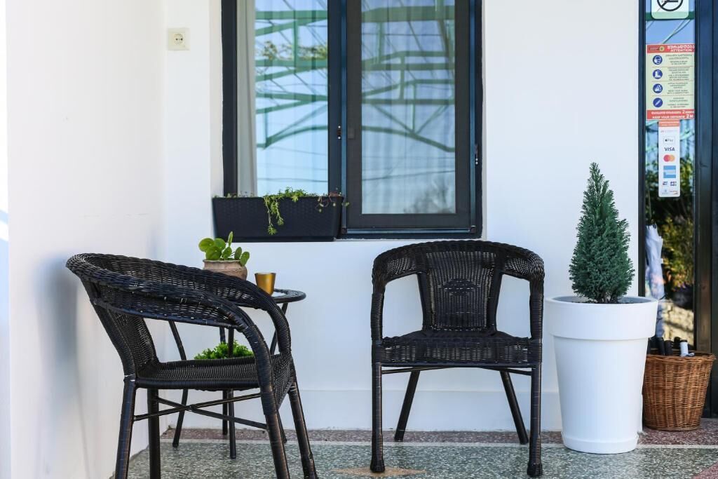 Duas cadeiras de vime e uma mesa pequena em frente a um edifício com janela.