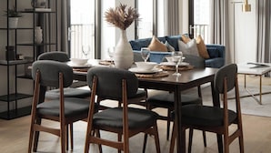 Uma sala de jantar moderna com uma mesa redonda, seis cadeiras e um sofá ao fundo.