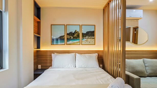 Quarto de hotel com uma cama, um sofá e três quadros na parede.