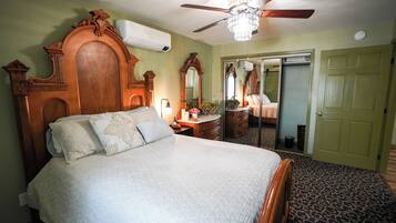 Quarto com cama grande, cabeceira de madeira, ventilador de teto e espelho.