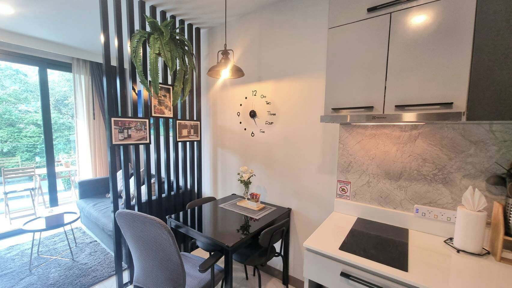 Cozinha moderna com área de refeições, um relógio na parede e uma planta.