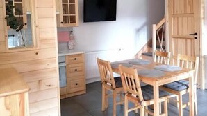 Interior de madeira com área de jantar, armários de madeira, televisão e escada.