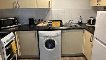 Uma cozinha compacta equipada com micro-ondas, torradeira, pia e máquina de lavar louça.