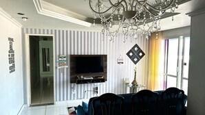 Uma cozinha moderna com televisão embutida, um candelabro e um espaço de refeições com cadeiras.