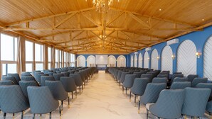Uma sala de conferência com fileiras de cadeiras, teto de madeira e amplas janelas.