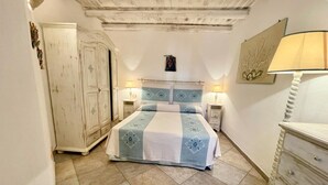 Um quarto com uma cama, duas mesas de cabeceira, um guarda-roupa e um abajur.
