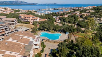 Vista aérea de uma área residencial costeira com uma grande piscina cercada por casas e vegetação.