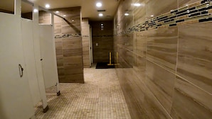 Um corredor estreito com piso ladrilhado, uma porta à esquerda e uma parede com desenho decorativo à direita.
