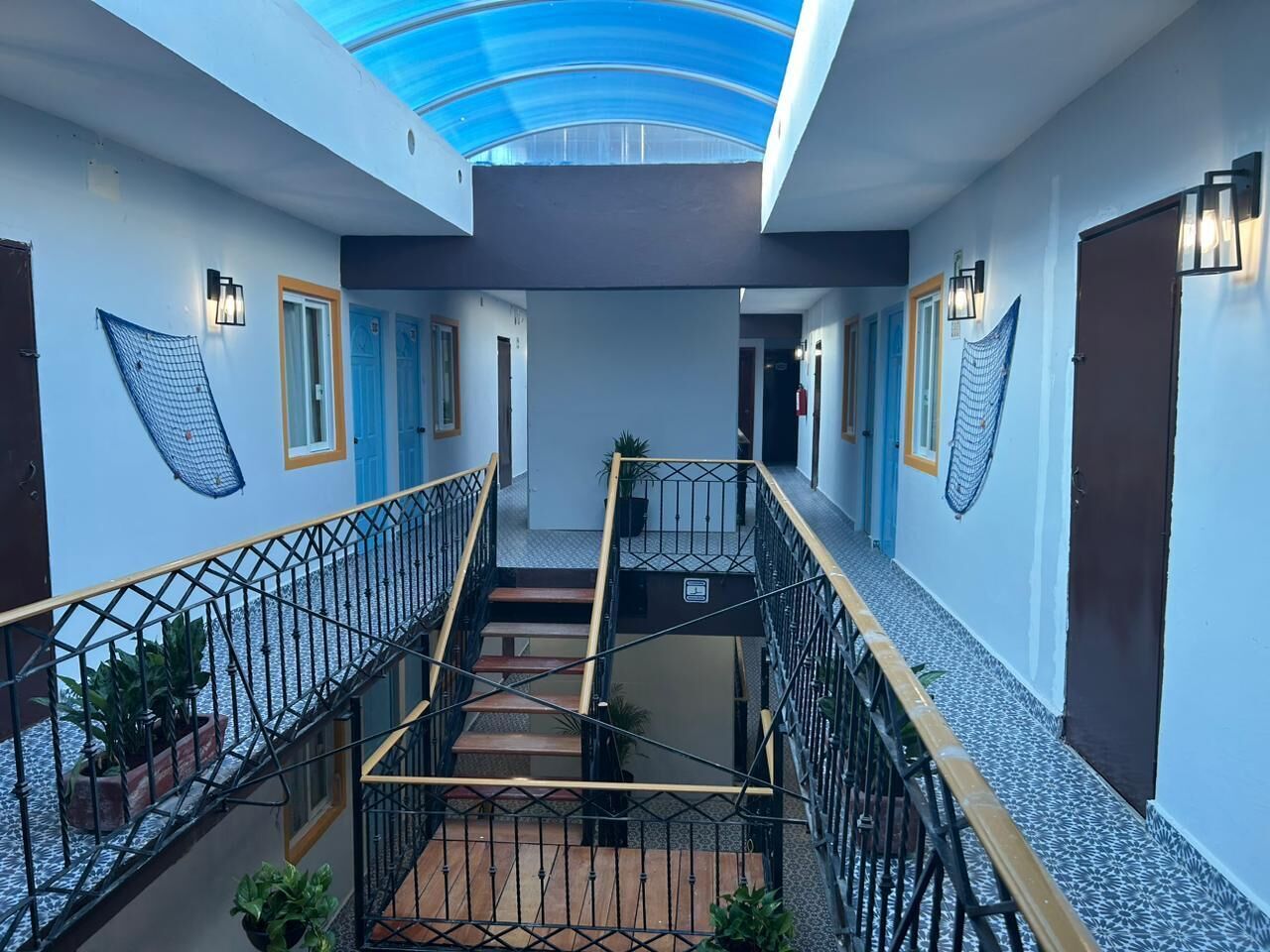 Interior com vários níveis, uma escadaria central, corrimãos e um claraboia.
