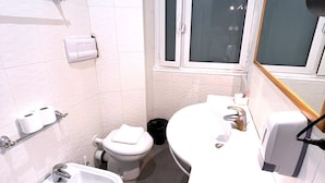 Um banheiro moderno com vaso sanitário, bidê, pia e espelho.