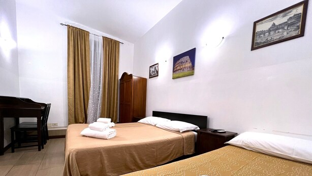 Quarto de hotel com duas camas, uma escrivaninha e um guarda-roupa.