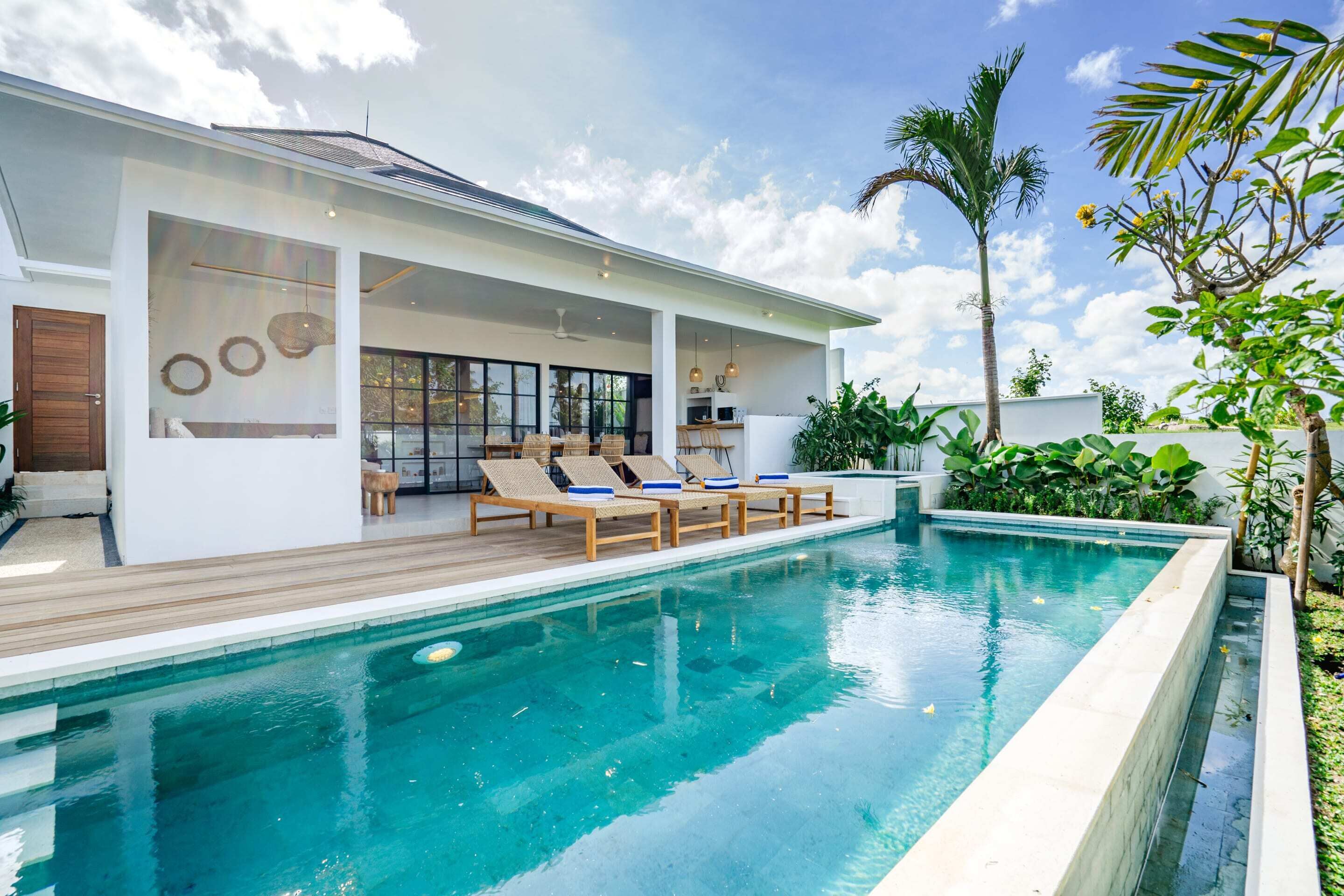 Uma casa moderna com piscina, espreguiçadeiras e um espaço de estar ao ar livre.