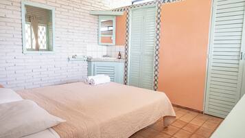 Quarto com cama, penteadeira, espelho e guarda-roupa.