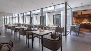 Uma sala de jantar moderna com divisórias de vidro, várias mesas e cadeiras.