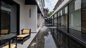 Um edifício moderno com um espelho d'água, área de estar ao ar livre e arquitetura tradicional ao fundo.