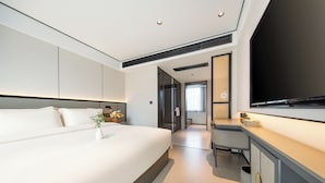 Quarto de hotel moderno com uma cama grande, uma escrivaninha e uma televisão.