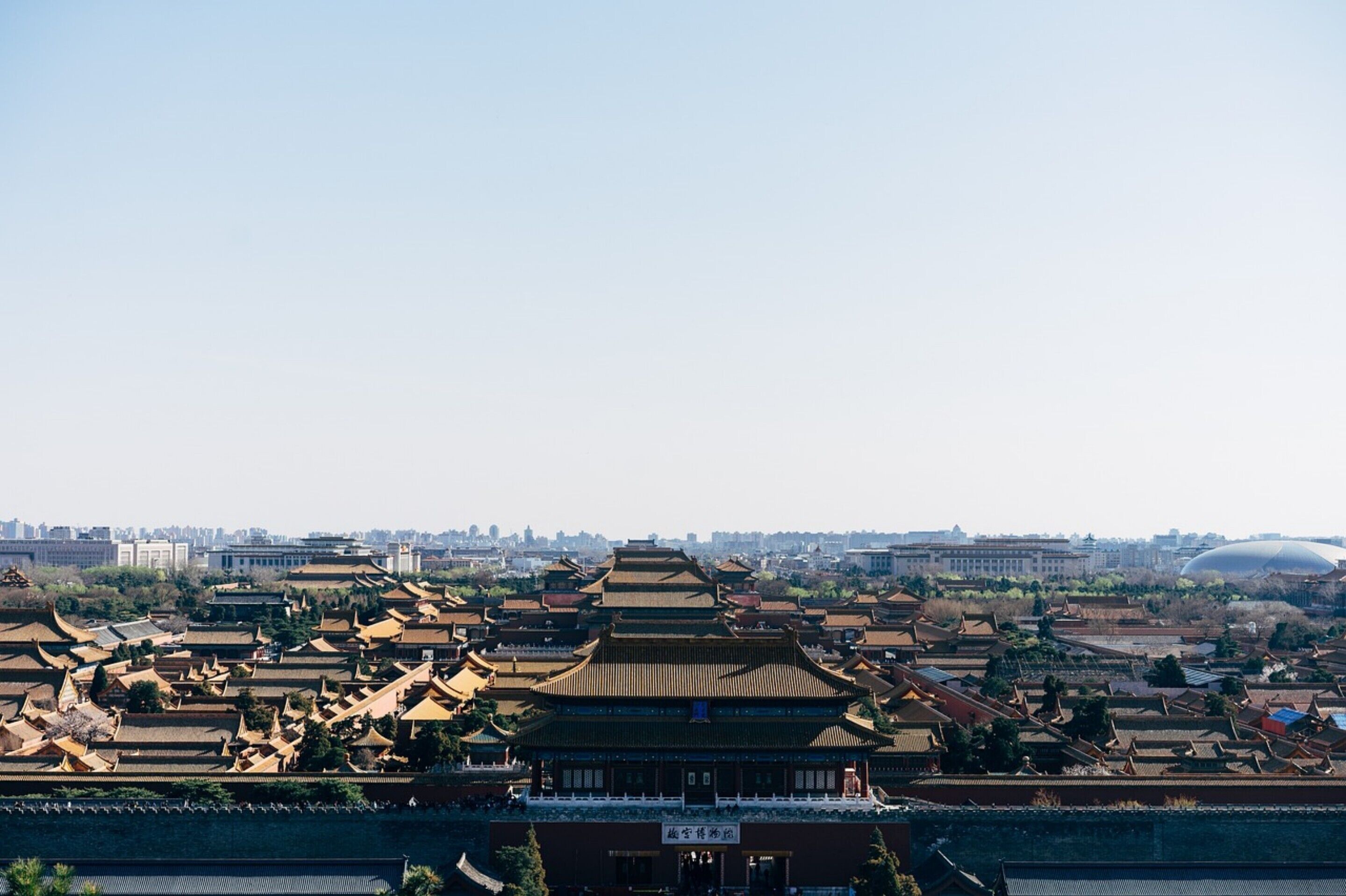 Um complexo arquitetônico tradicional chinês com vários edifícios, incluindo uma estrutura notável com telhado telhado e uma placa.