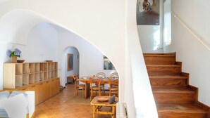 Uma sala de estar ampla com uma mesa de jantar, cadeiras e uma escada de madeira.