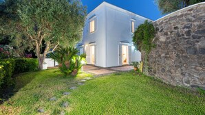 Uma casa de dois andares com uma parede de pedra e um jardim bem cuidado.