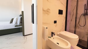 Uma casa de banho moderna com bidé, sanita e cabine de duche em vidro.