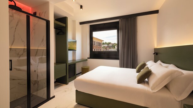 Quarto moderno com cama grande, closet espaçoso e janela com vista para edifícios.