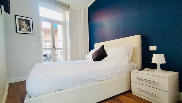 Quarto com cama, mesa de cabeceira e apoio para objetos pessoais.