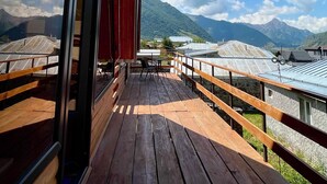 Um deck de madeira com vista para montanhas e céu claro.