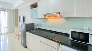 Uma cozinha moderna com eletrodomésticos de aço inoxidável, armários de madeira clara e uma TV de tela plana instalada acima do balcão.