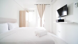 Quarto de hotel com uma cama grande, TV fixada na parede e vista para o exterior pela janela.