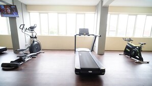 Uma academia com esteira, elíptico e bicicleta ergométrica.