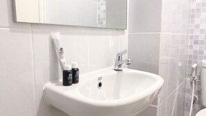 Casa de banho com uma pia branca, um espelho e duas embalagens de produtos de higiene pessoal.
