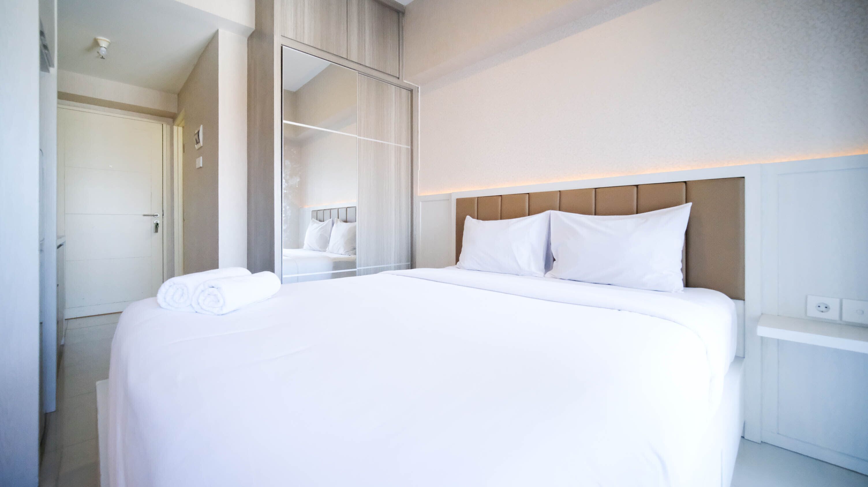 Quarto de hotel com uma cama grande, um guarda-roupa e um espelho.