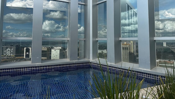 Piscina interior moderna com amplas janelas que oferecem vista para a cidade.