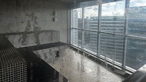 Interior de um edifício alto com uma janela grande que dá para a paisagem urbana.