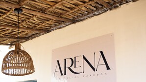 Placa para 'ARENA Hostel del Paredon' com teto rústico e porta azul.