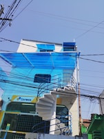 Um edifício com fachada azul e branca, com uma placa visível para 'Correios', e uma escadaria em espiral.