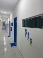 Um corredor comprido e estreito com portas azuis e um extintor fixado na parede.