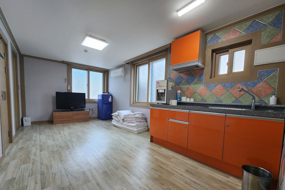Uma cozinha moderna com armários cor de laranja, forno embutido e painel de azulejos.