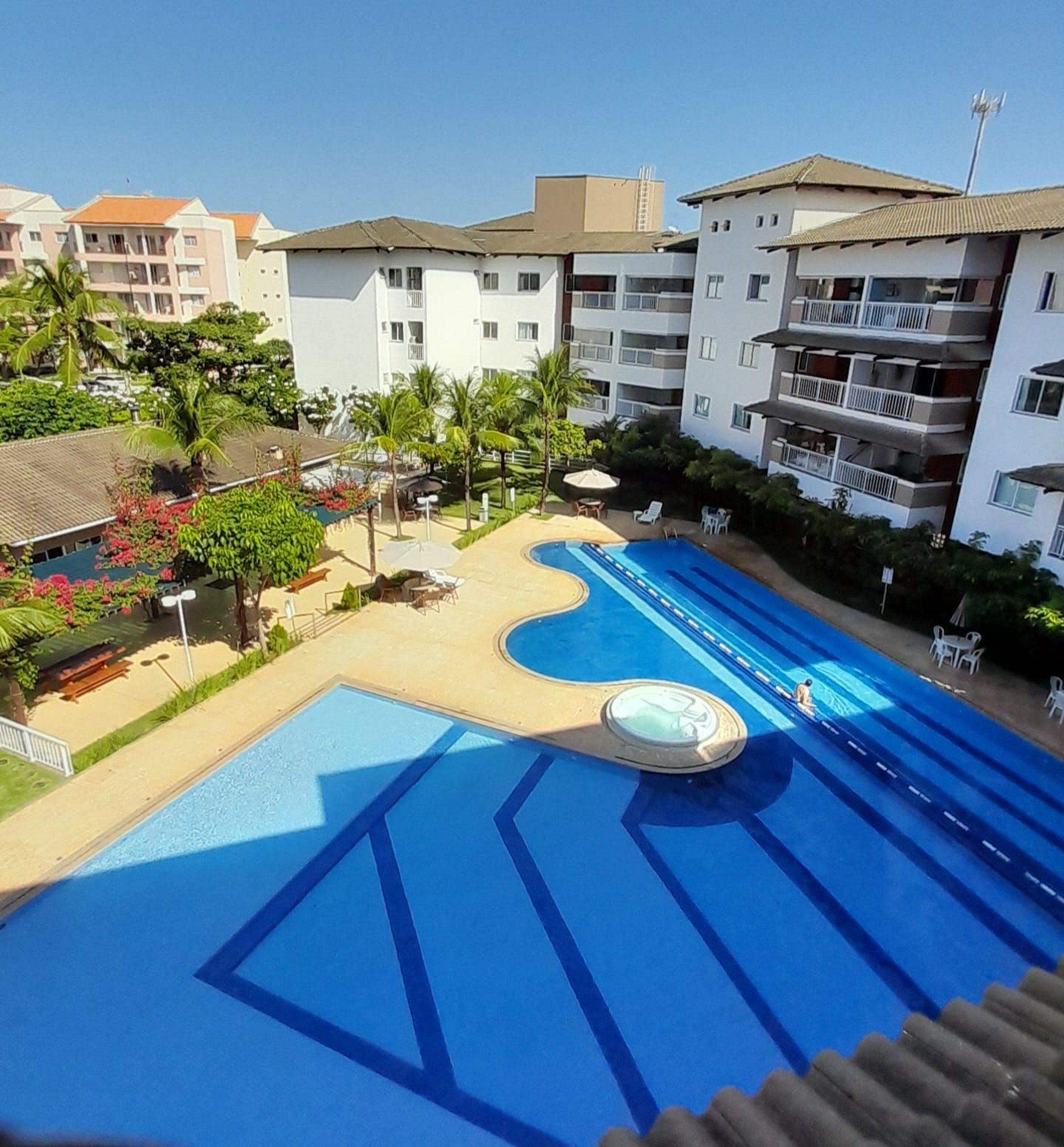 Hotel com piscina, várias varandas e vegetação exuberante.