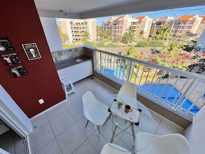Varanda com mesa de jantar, cadeiras, um banquinho pequeno e um vaso com planta.