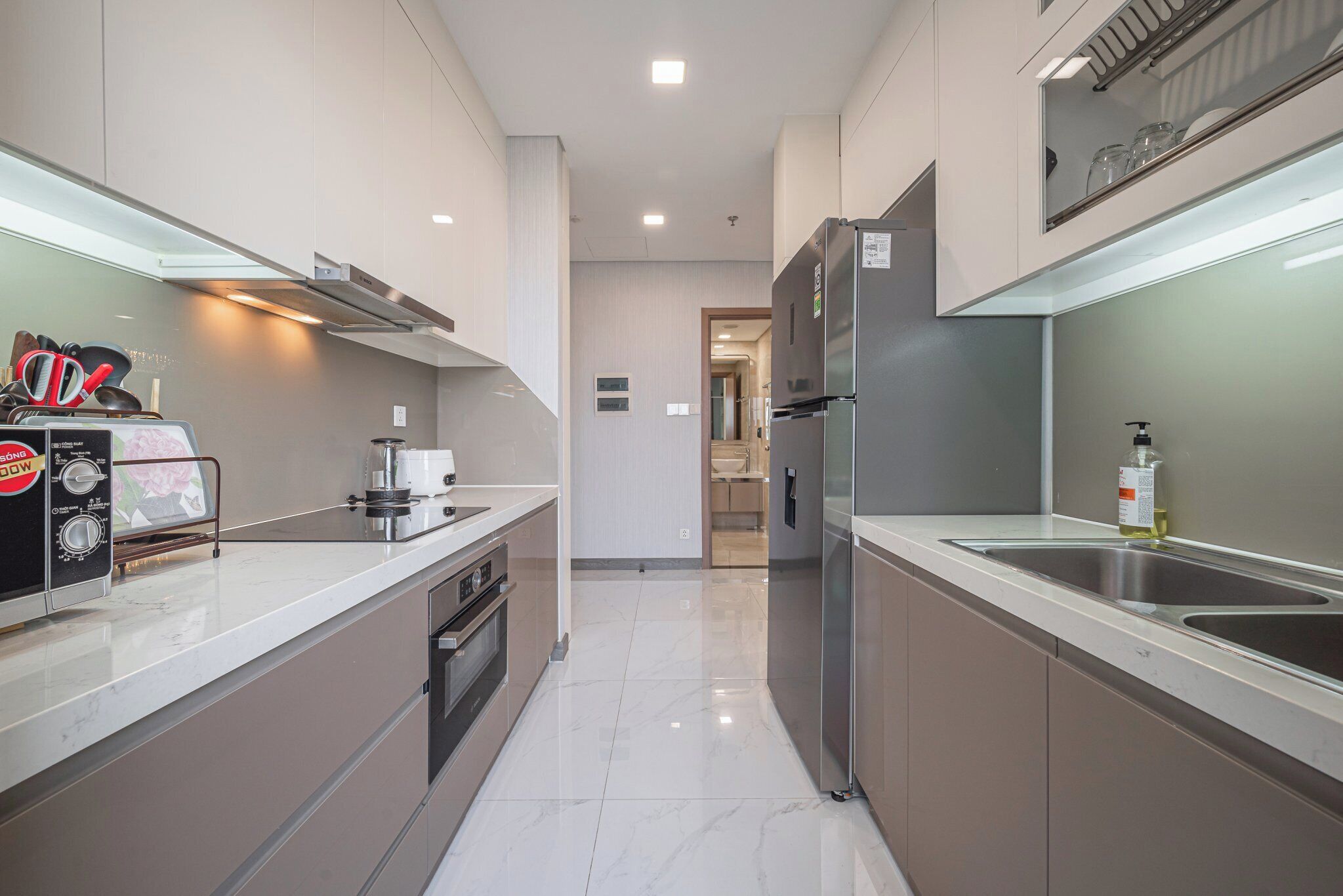 Uma cozinha moderna com eletrodomésticos de aço inoxidável, bancada de mármore e dispensa espaçosa.