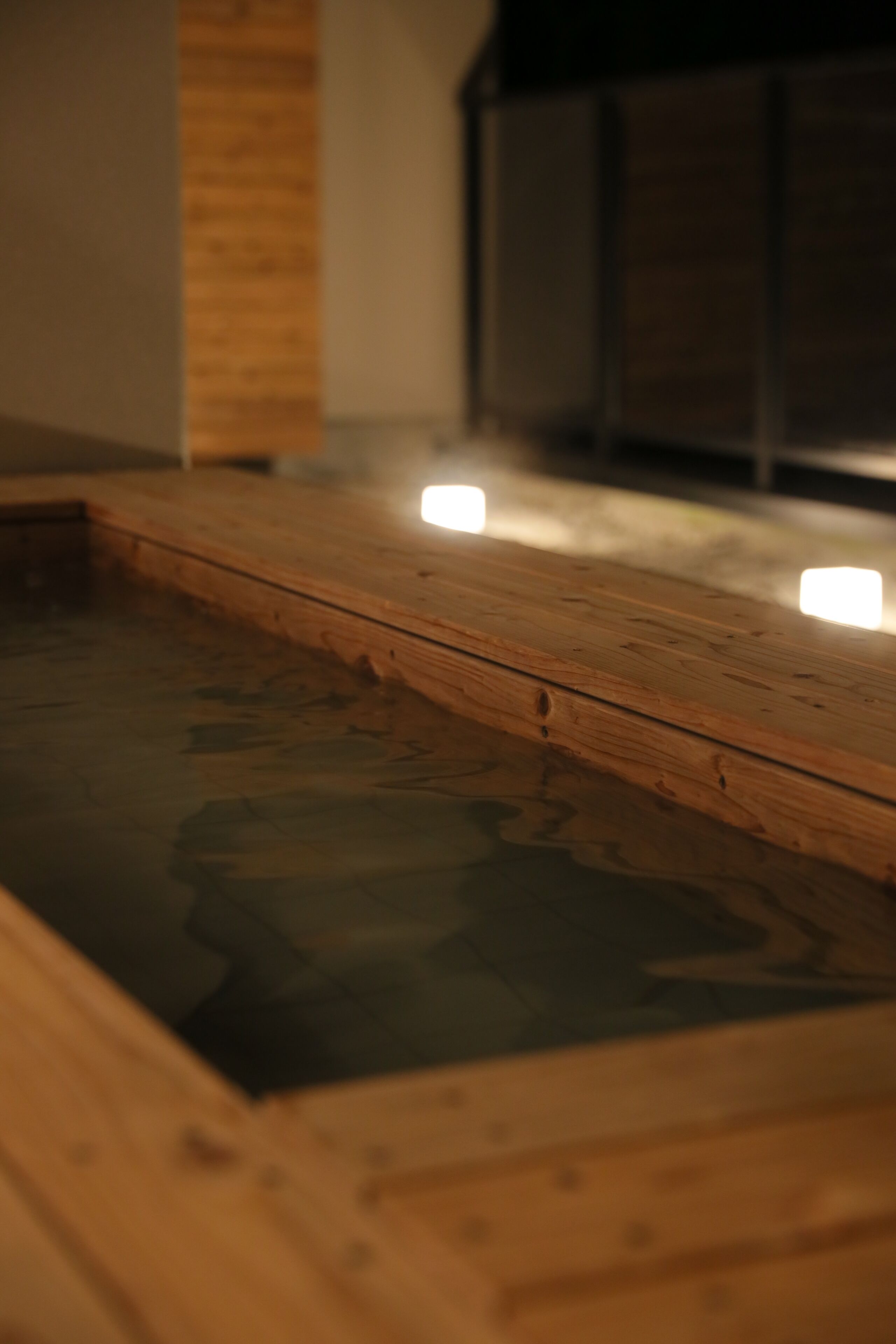Uma sauna de madeira com piso inclinado e uma pequena piscina.