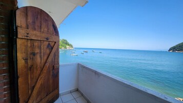 Varanda com vista para o mar, porta de madeira e chão de azulejos.