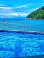 Visão nítida de uma piscina com borda azulejada e um veleiro ao fundo.