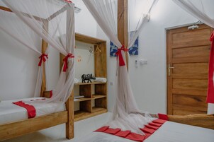 Quarto com duas beliches de madeira, cada uma com colcha de dossel e detalhes vermelhos.