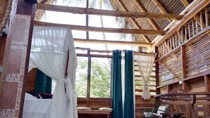 Um quarto rústico de madeira com cama, banco e mesa.