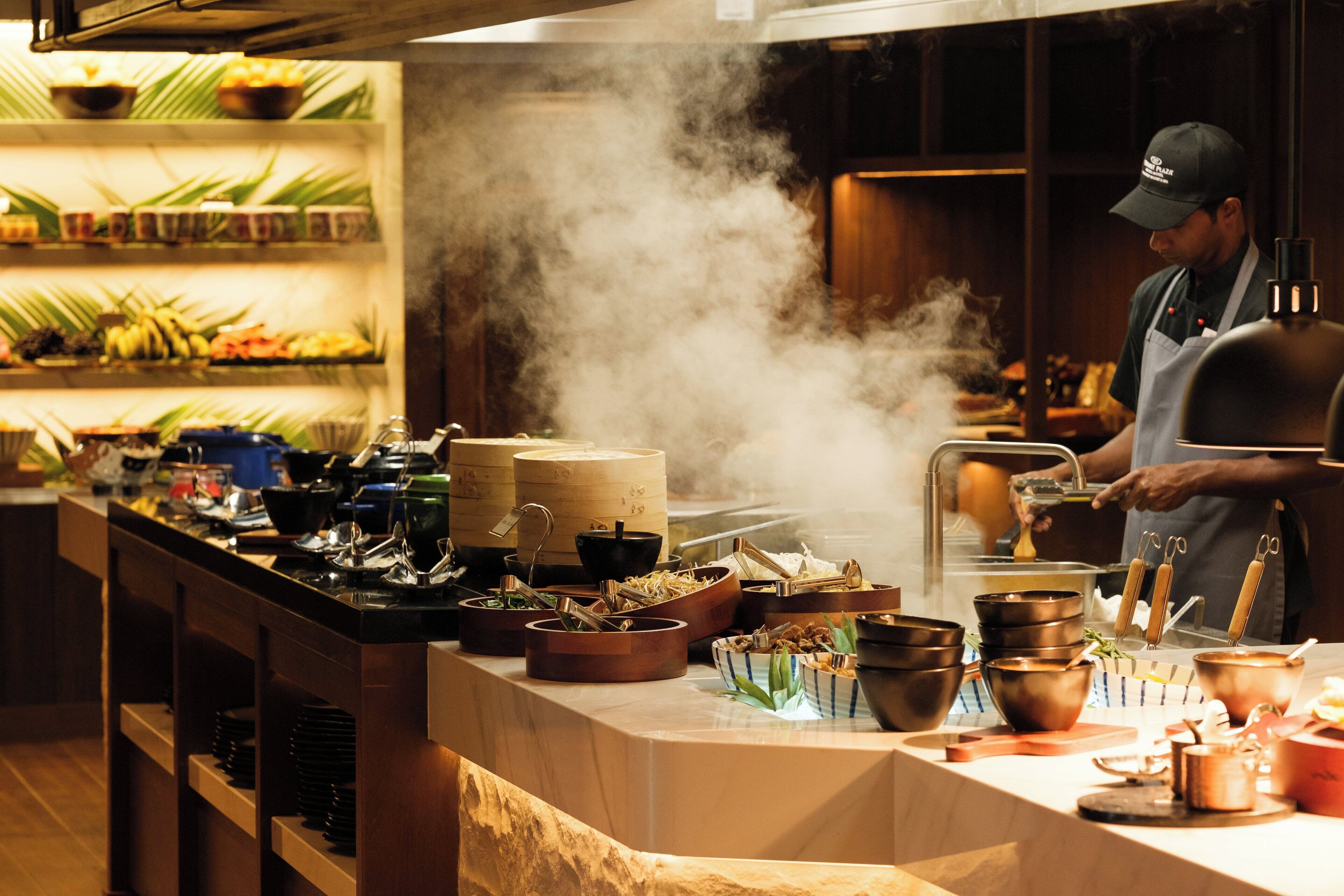 Uma cozinha com diversos utensílios e equipamentos de cozinha, incluindo panelas, frigideiras e um prato fumegante.