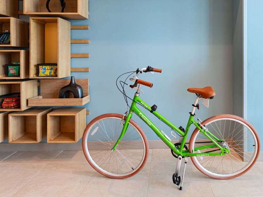 Uma bicicleta verde com detalhes em castanho, prateleiras de madeira com vários objetos e uma parede azul.