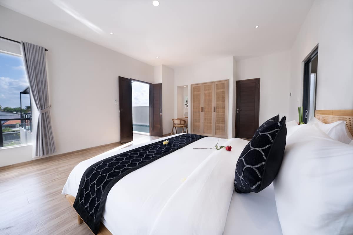 Quarto de hotel moderno com uma cama grande, vista para o exterior e varanda.